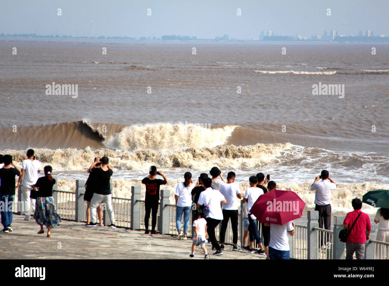 Visitors and local residents watch waves from a tidal bore of Qiantang ...