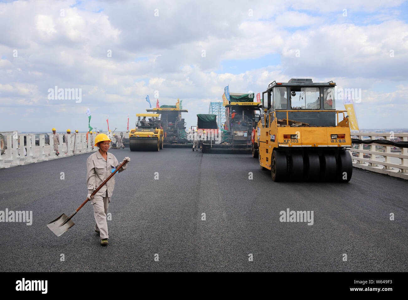 Chinese workers operate road paver to paint bitumen on the world's ...