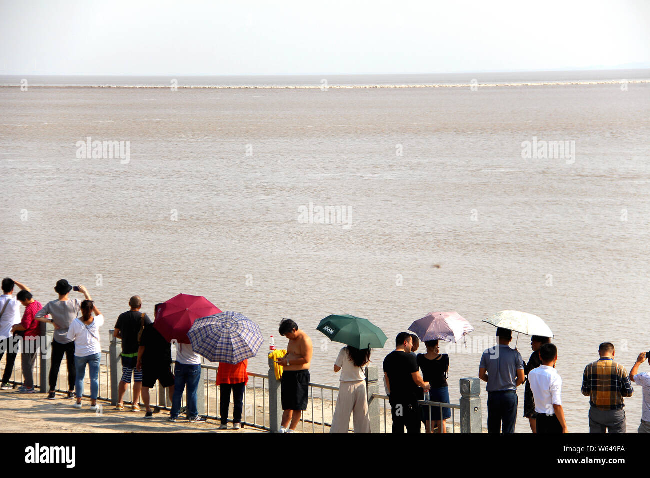 Visitors and local residents watch waves from a tidal bore of Qiantang ...