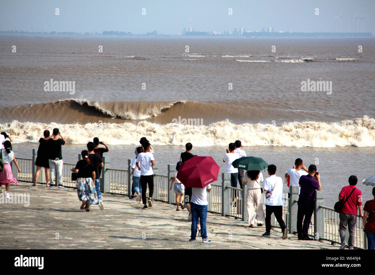 Visitors and local residents watch waves from a tidal bore of Qiantang River gushing over the ...