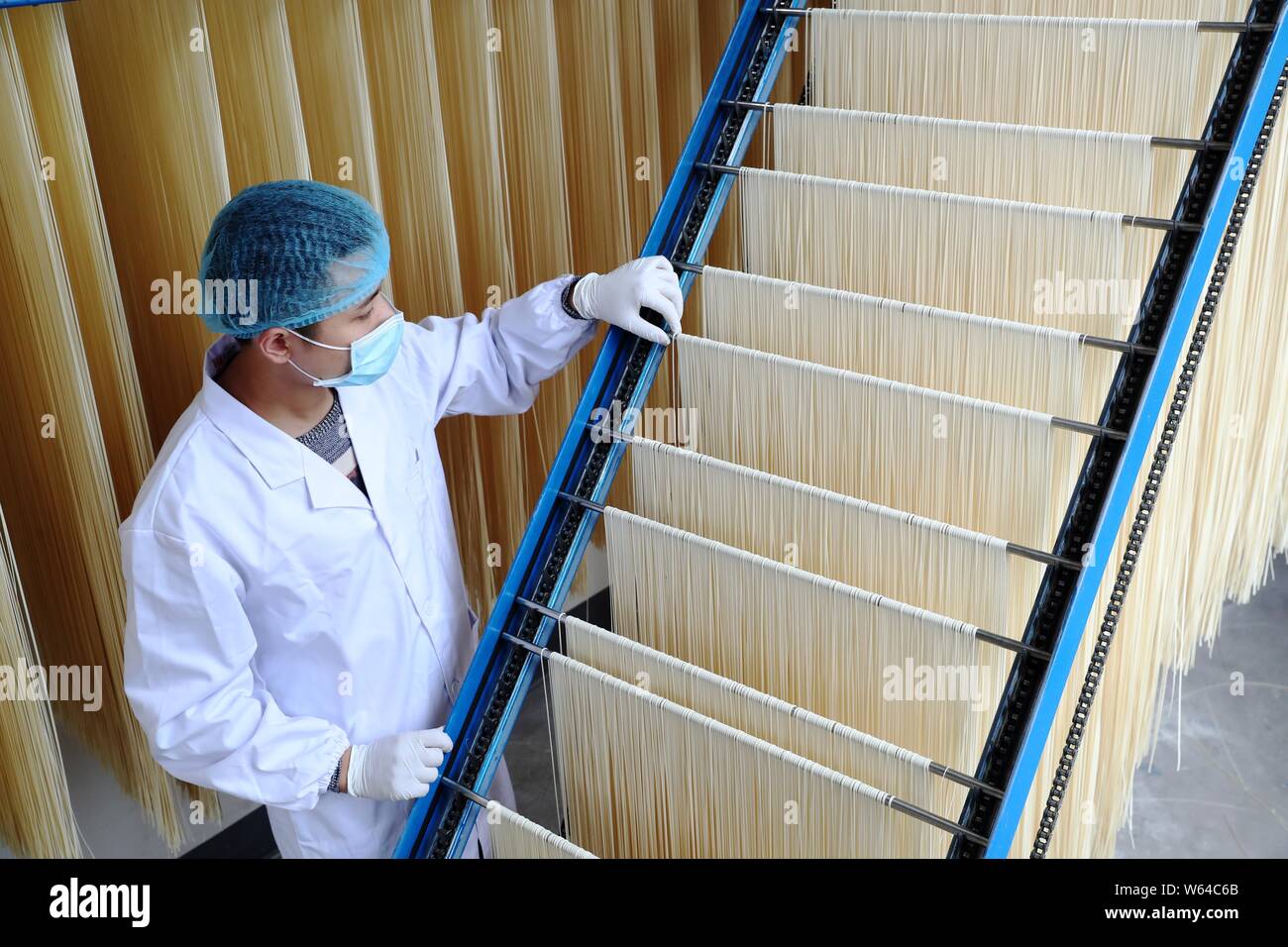 --FILE--A Chinese worker surveys the production of dry noodles at a ...