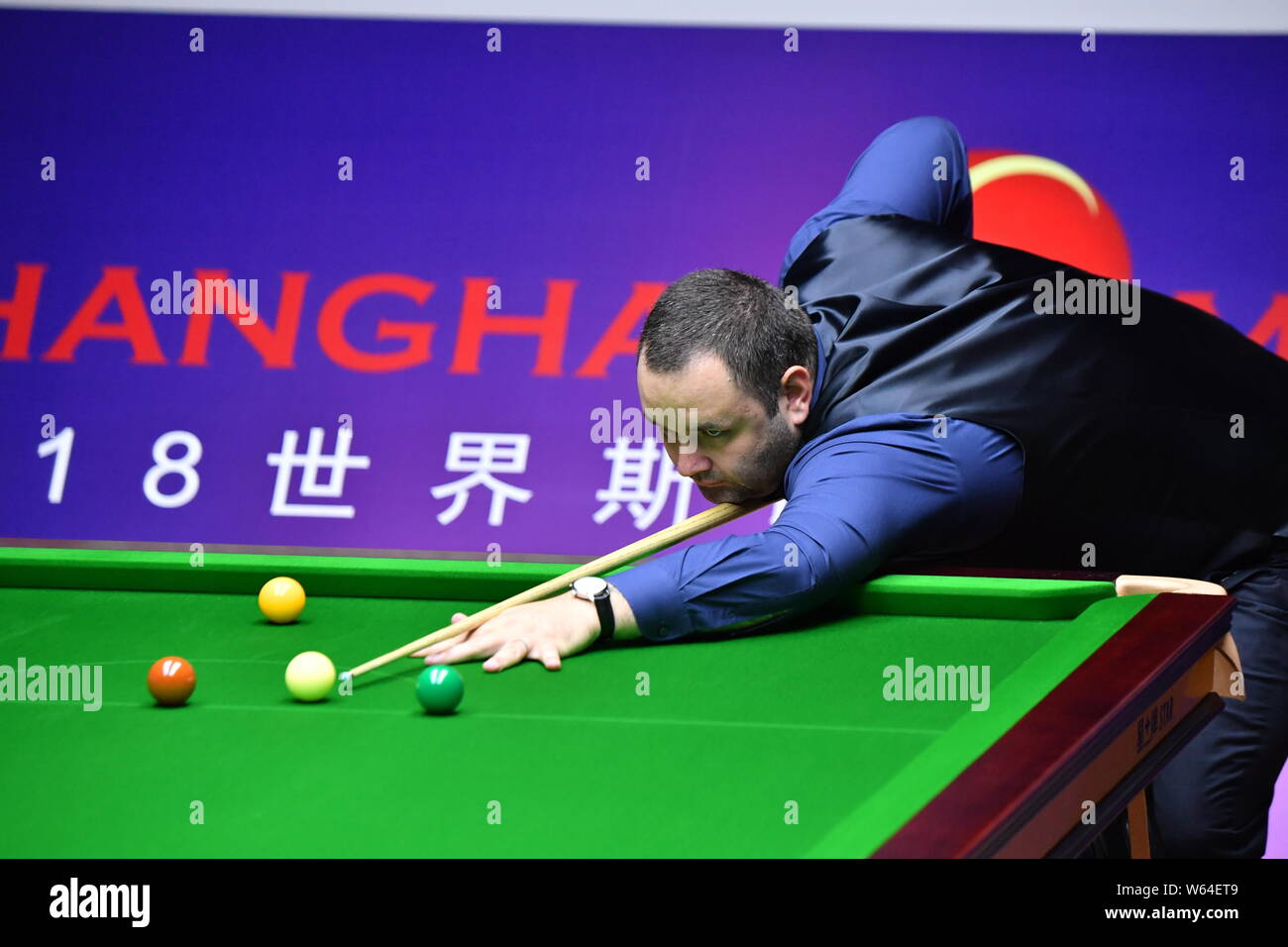 Stephen Maguire of Scotland plays a shot to Pu Qingsong of China in ...
