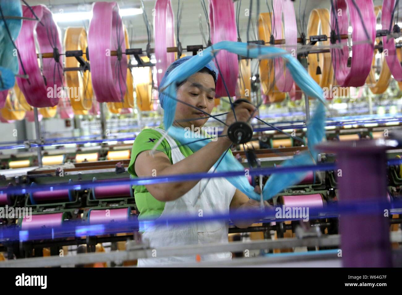 --FILE--A female Chinese worker handles production of silk at a textile ...