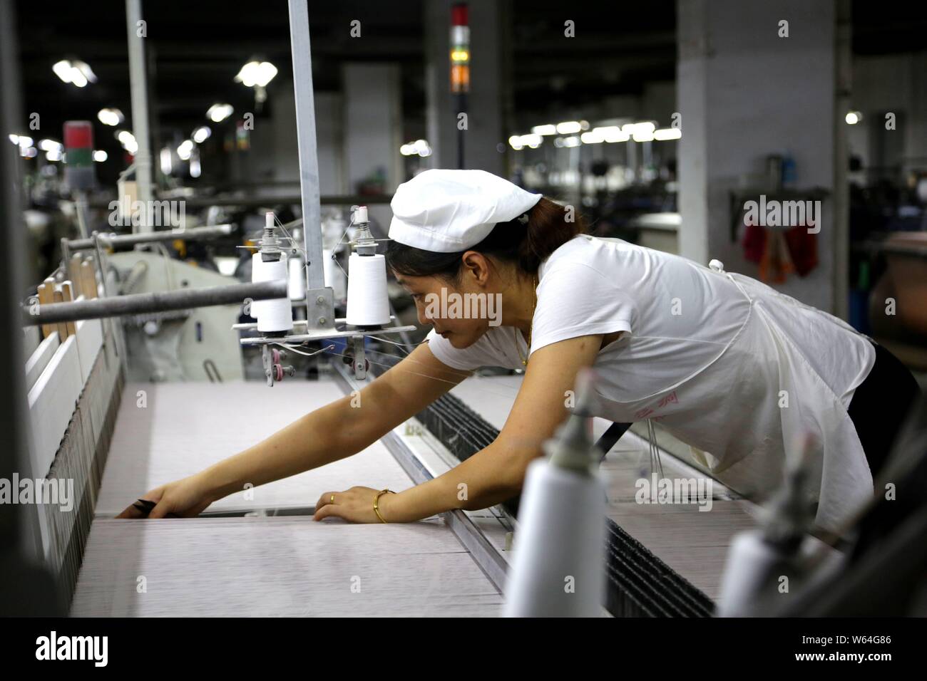 --FILE--A female Chinese worker handles production of silk at a textile ...
