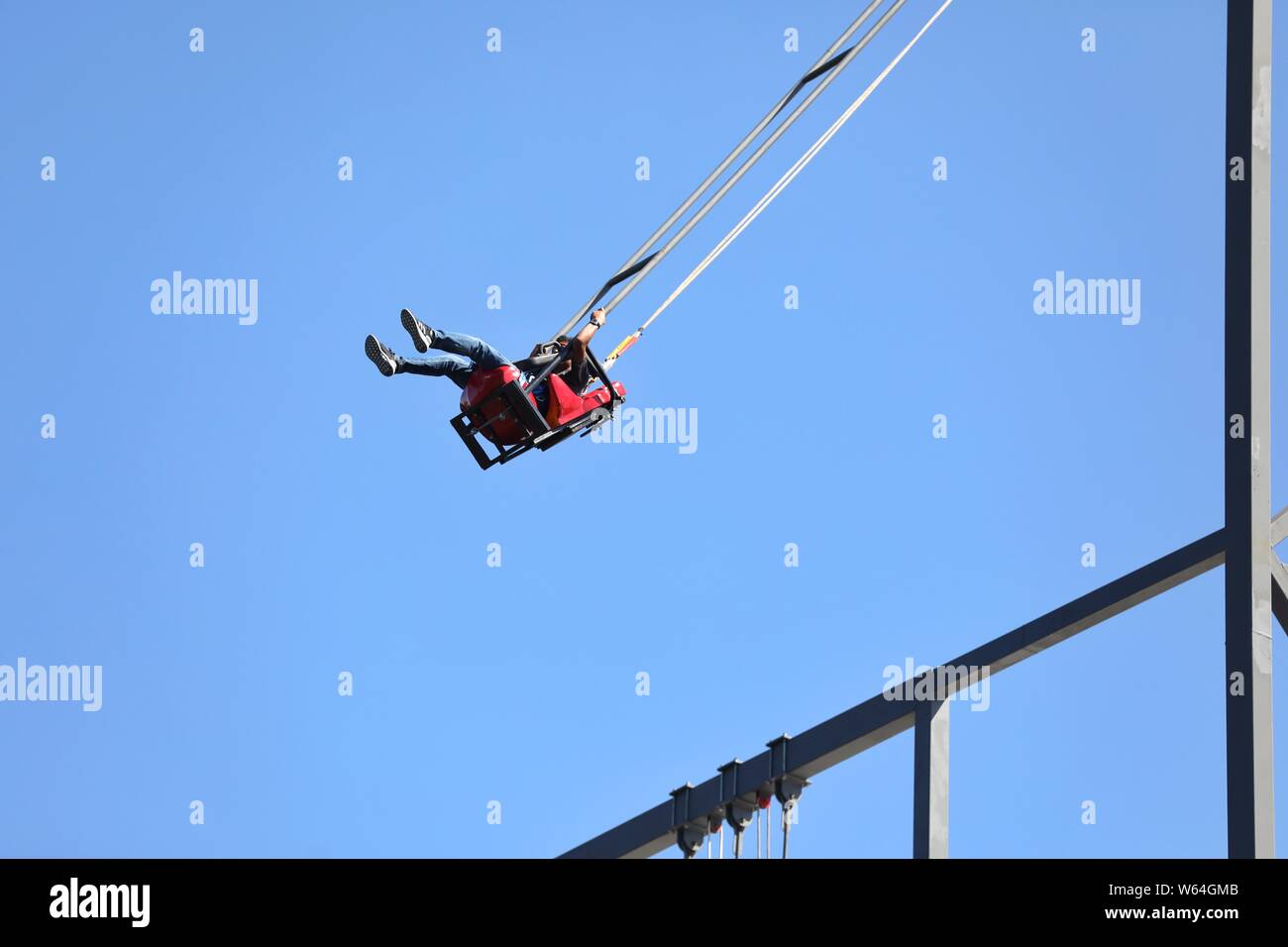 A tourist experiences a swing over the edge of a vertical cliff in a ...