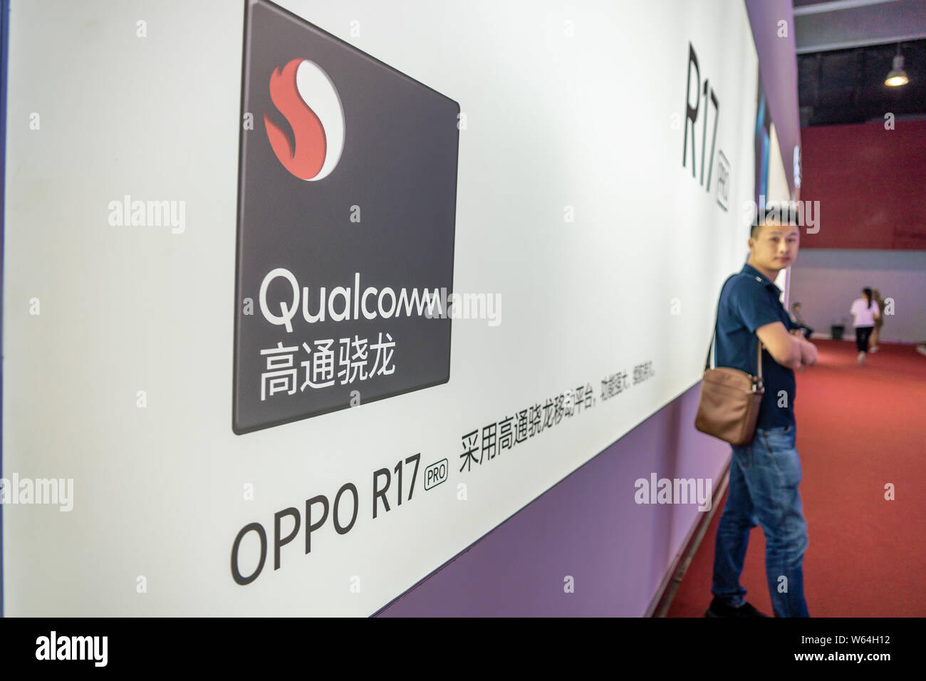 --FILE--A visitor walks past the stand of Qualcomm during an expo in ...