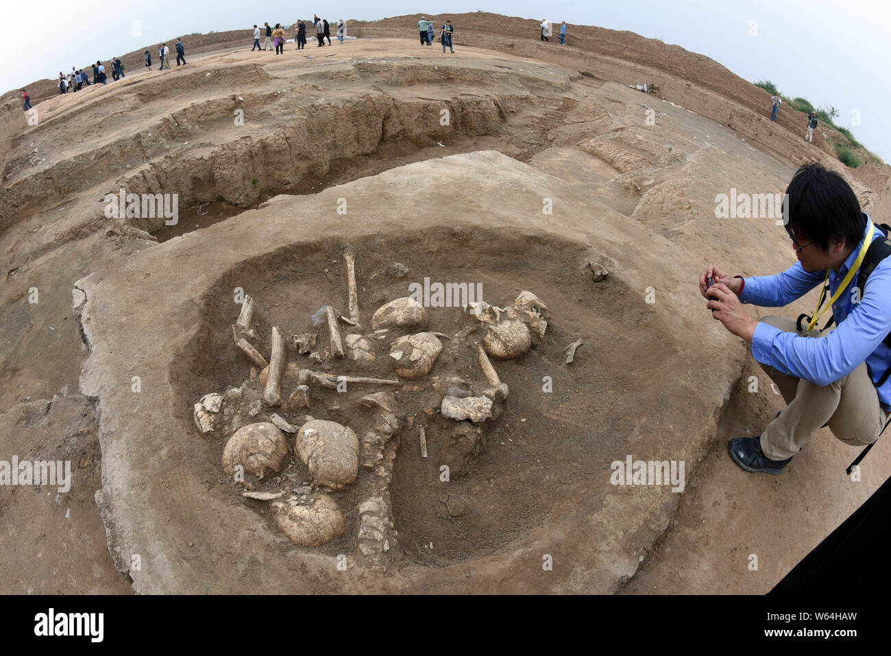 A visitor takes photos of pottery unearthed in the excavation site of ...