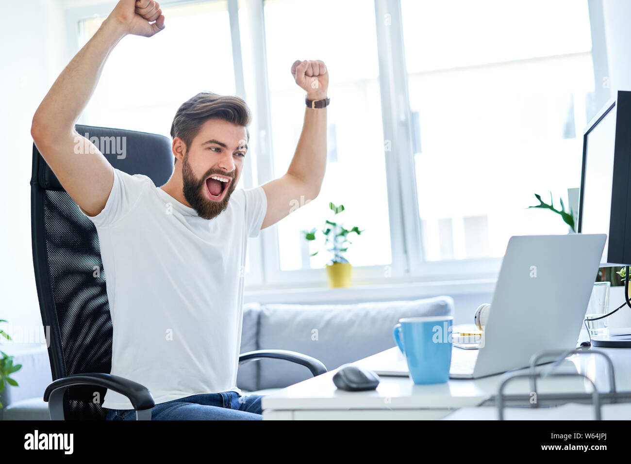 Excited successful man working in office looking on laptop Stock Photo ...