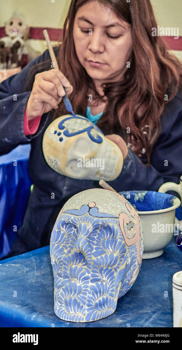Mexico, Puebla town, Focused mature woman painting pottery death's-head ...