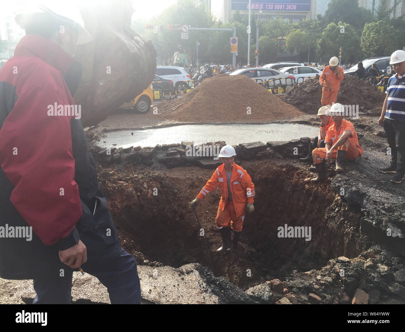 Chinese workers repair a broken water pipeline causing a road collapse ...