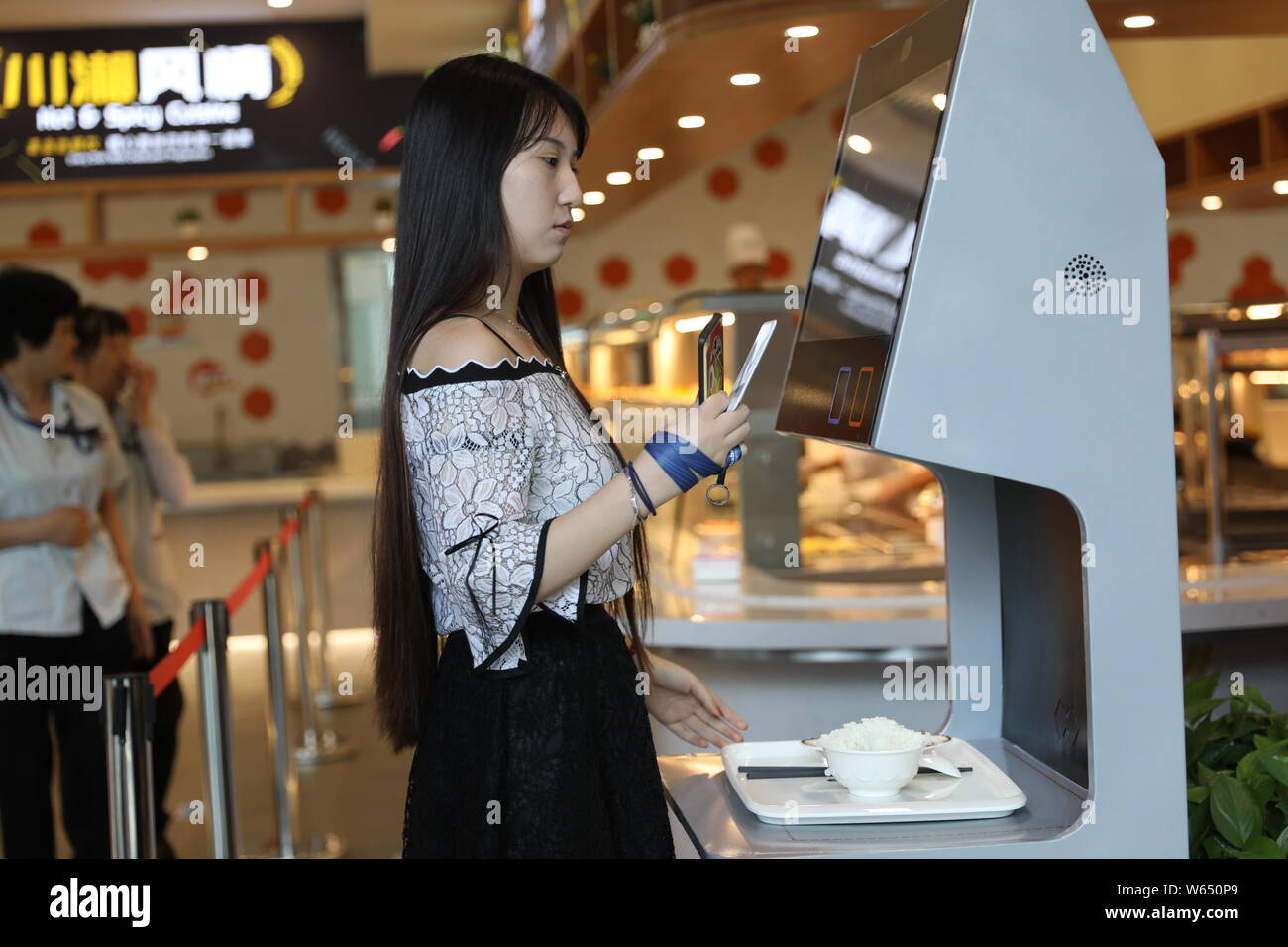 A Chinese employee has her employee card scanned by a self-service ...