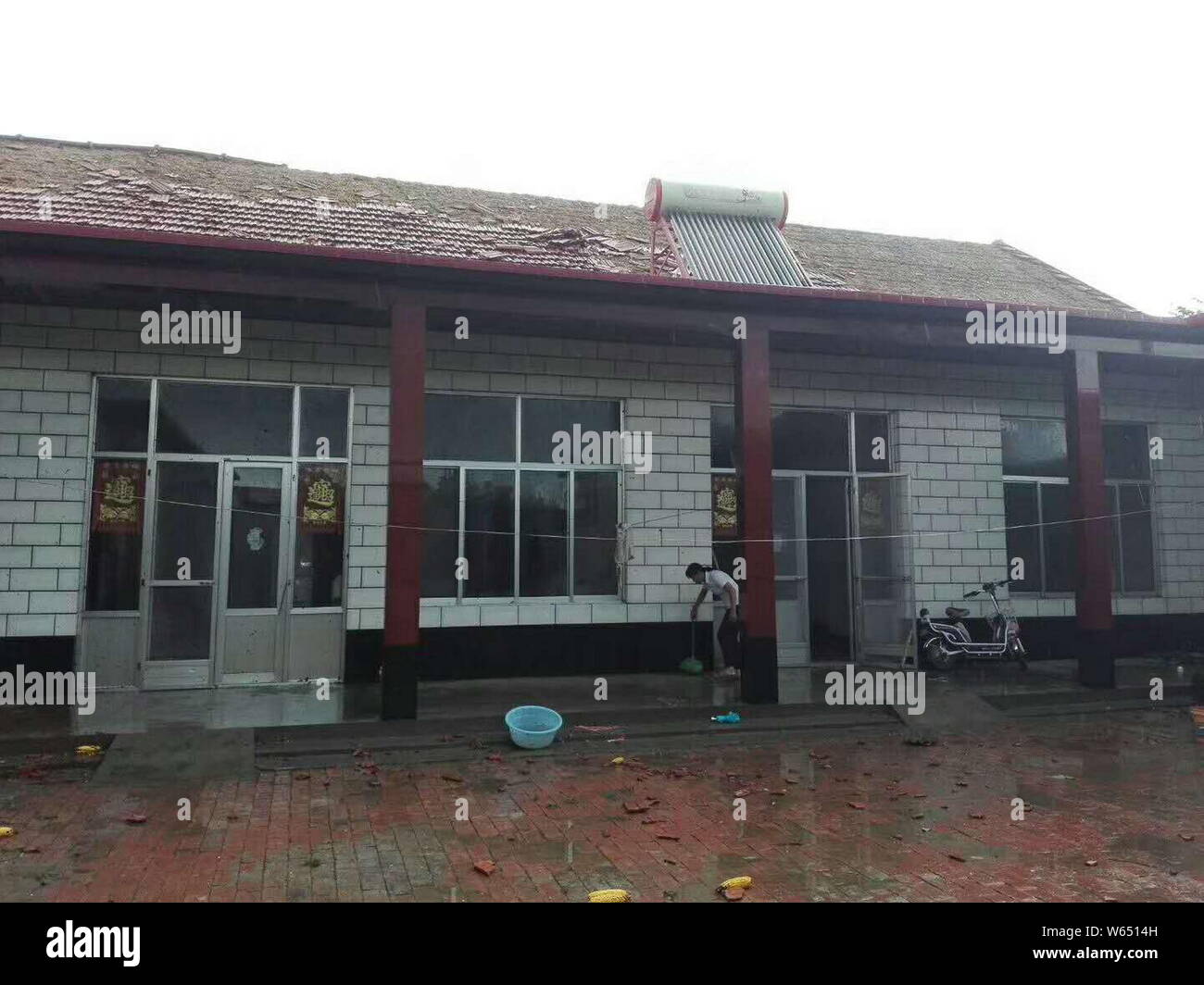 Tiles of the rooftop of a residential house are damaged by strong wind ...