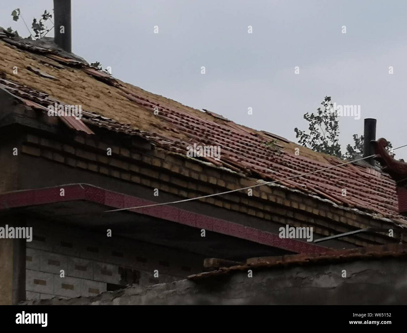 Tiles of the rooftop of a residential house are damaged by strong wind ...