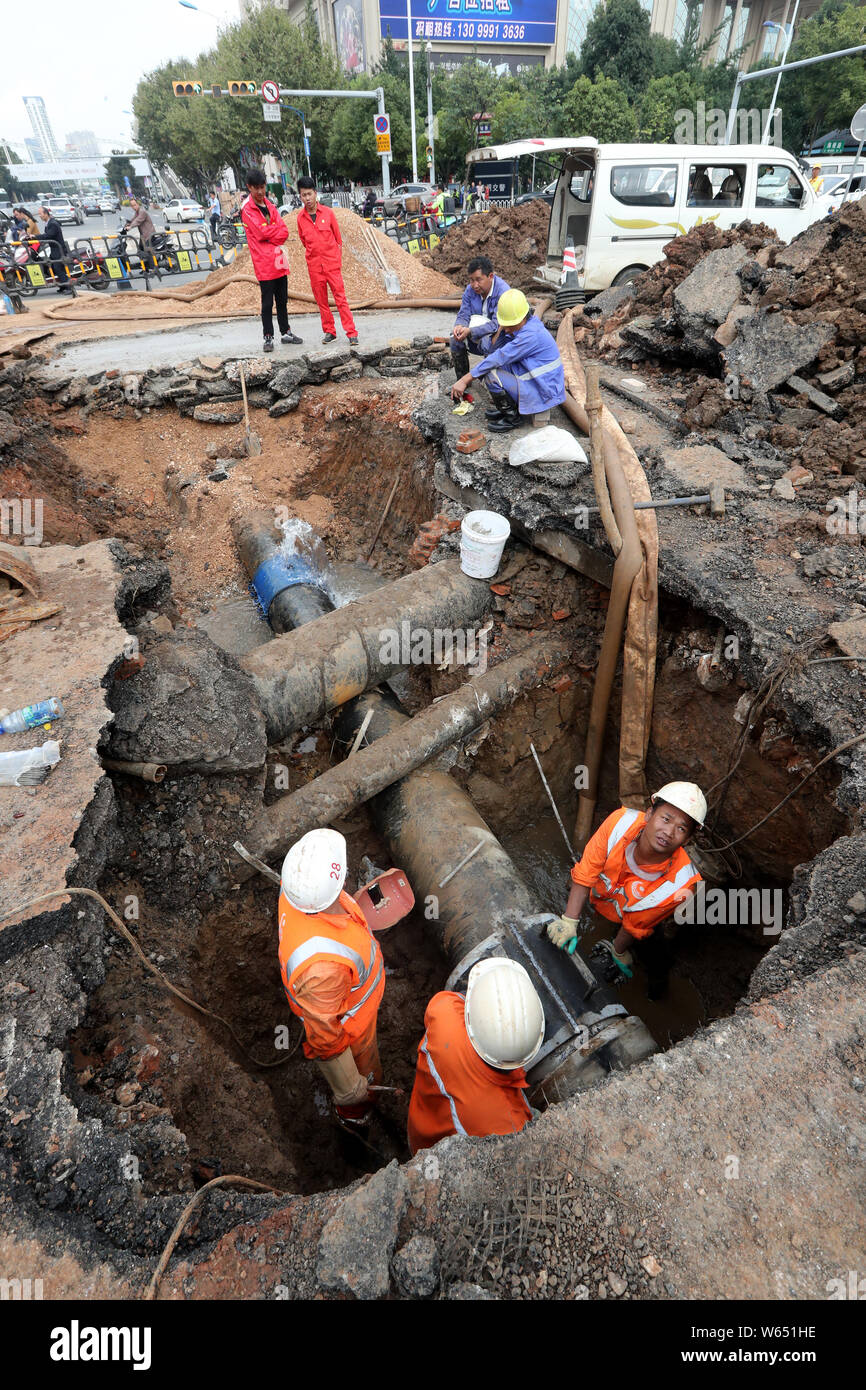 Chinese workers repair a broken water pipeline causing a road collapse ...