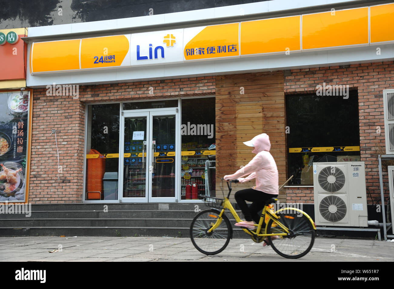 A cyclist rides past a closed outlet of Lin Jia Convenience Store in ...