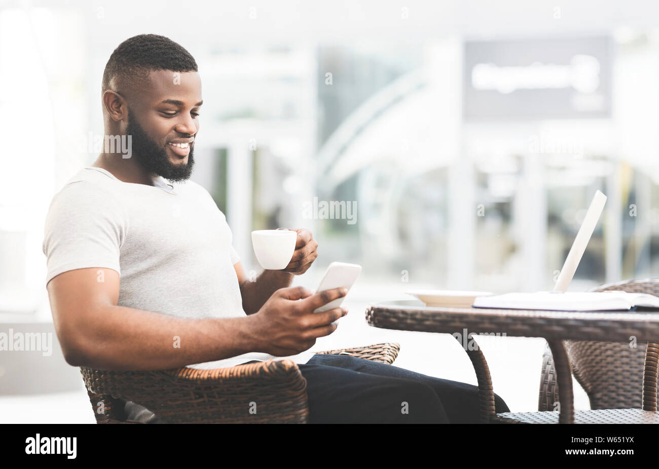 Handsome african man drinking coffee and reading Stock Photo - Alamy