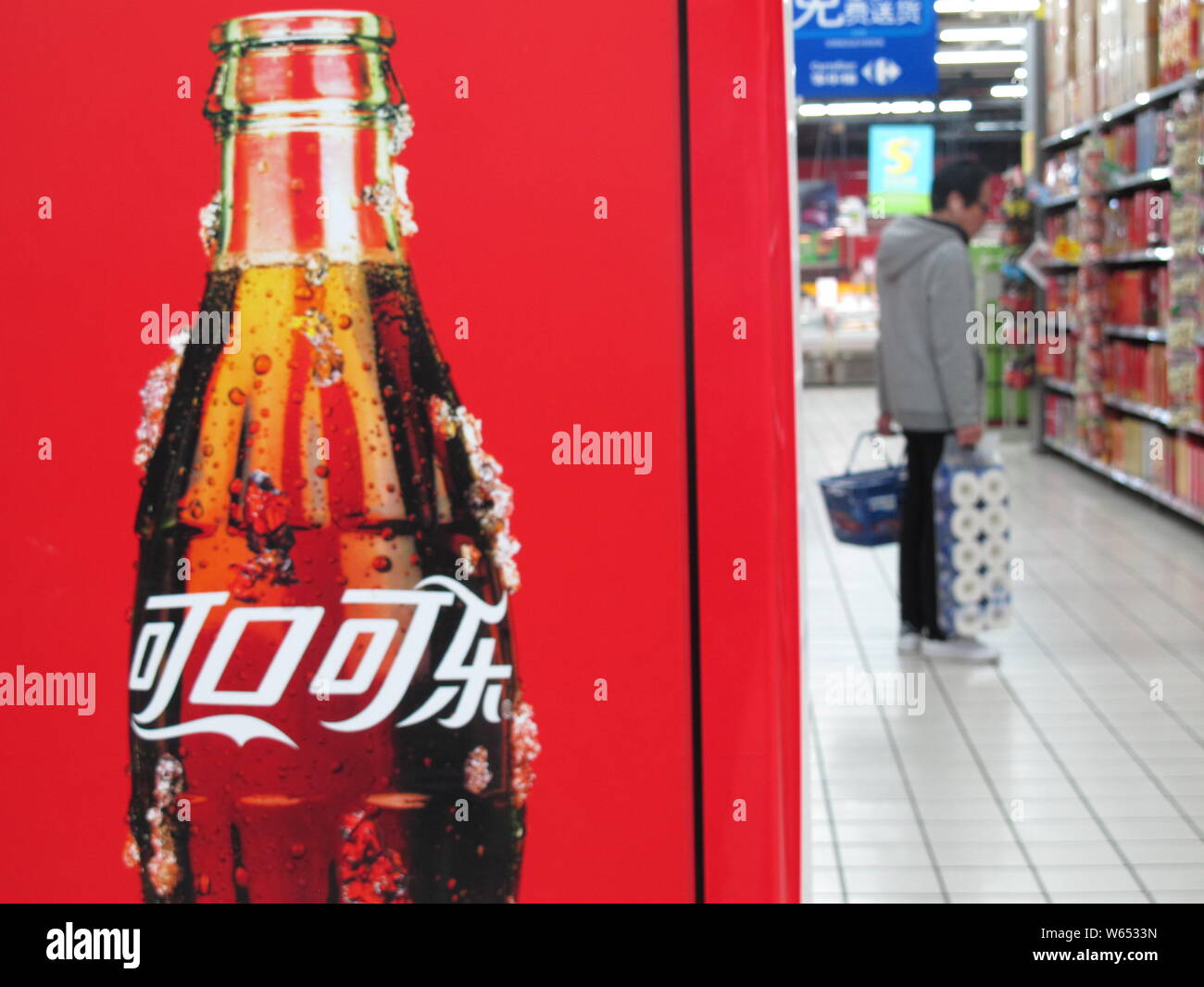 --FILE--Customers shop next to an advertisement for Coca-Cola coke at a ...