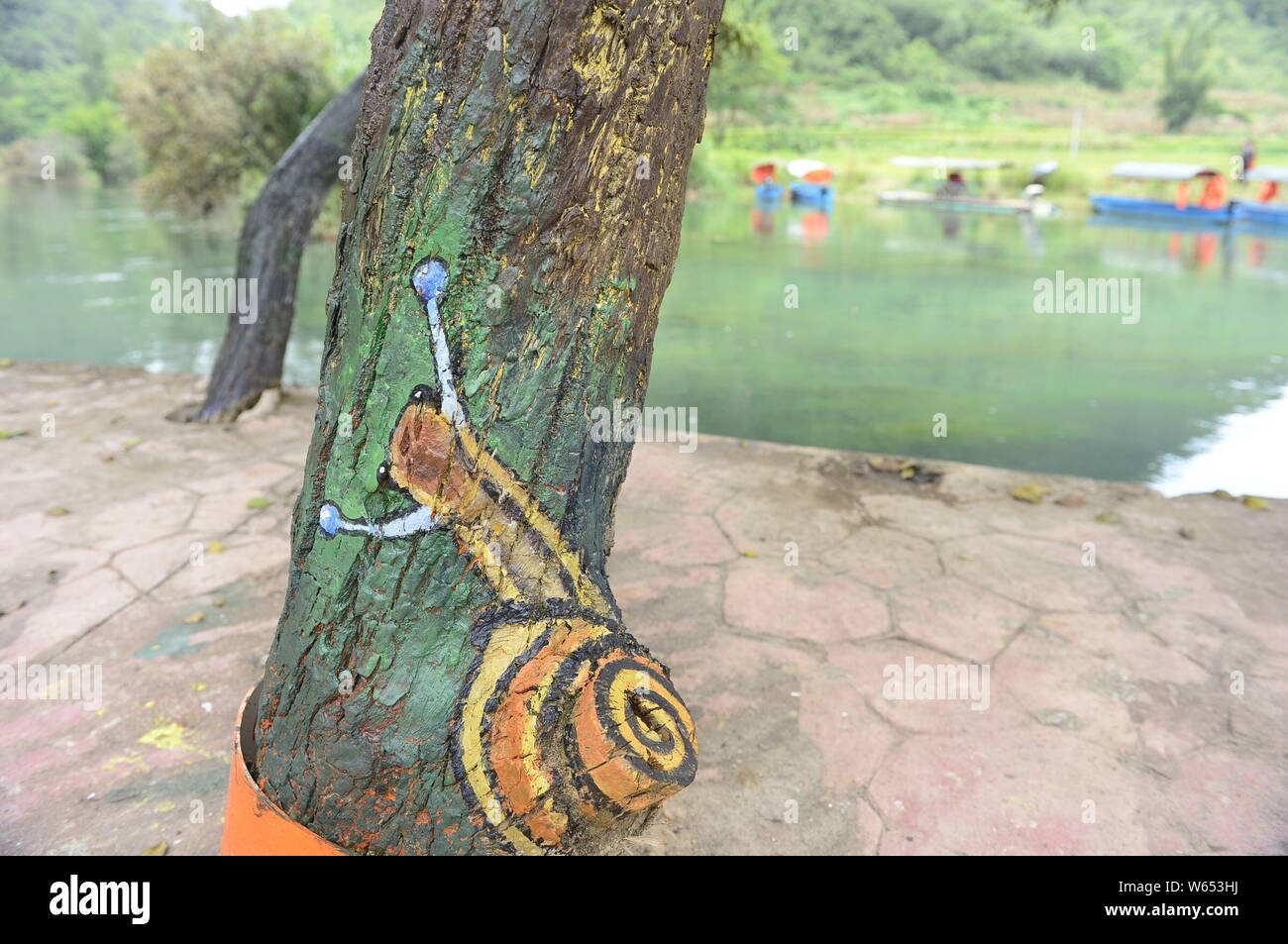 A colored drawing of a snail is seen on a tree in Heye village, Babao ...
