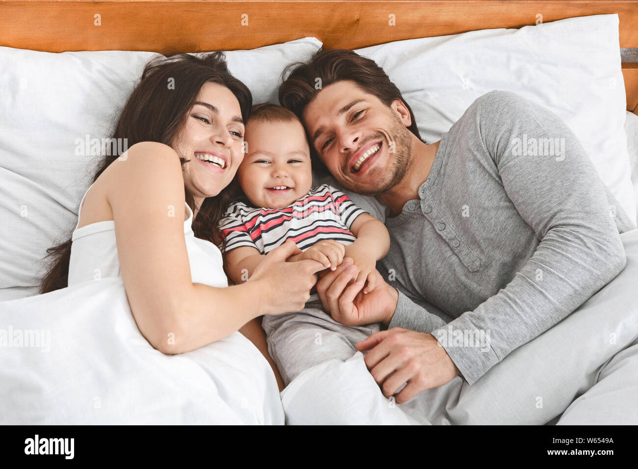 Happy parents waking up with cute toddler in bed Stock Photo - Alamy
