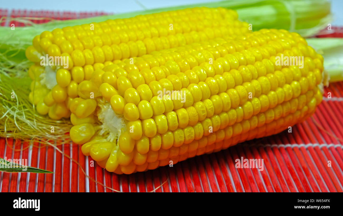 Sweet corn on a red texture Stock Photo - Alamy