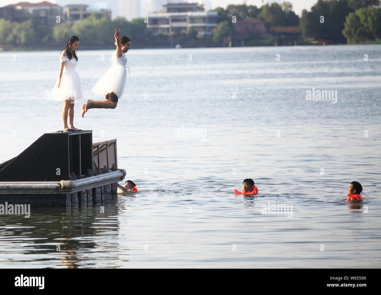 Participants wearing in wedding dresses jump into the East Lake to cool ...