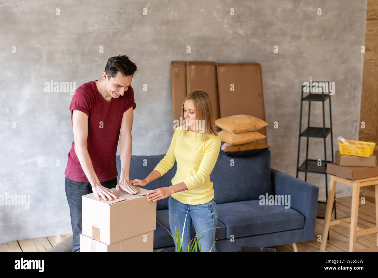 Happy people packing cardboard box, concept moving house. Young couple ...