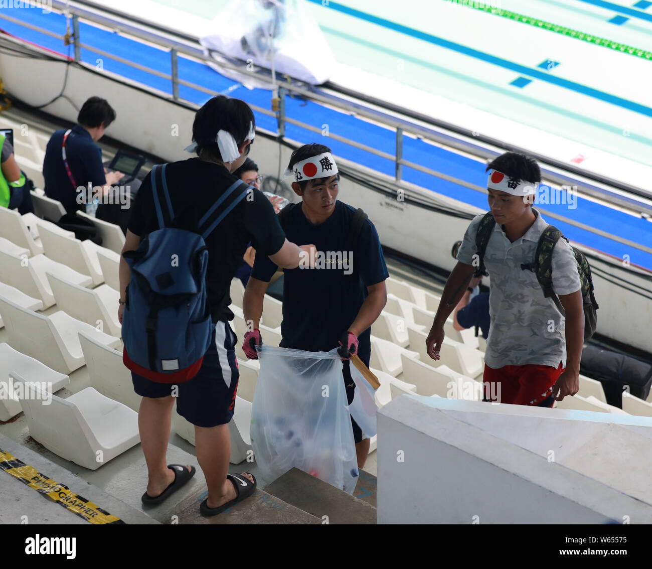 Japanese fans clean the natatorium's stand after a swimming match in ...