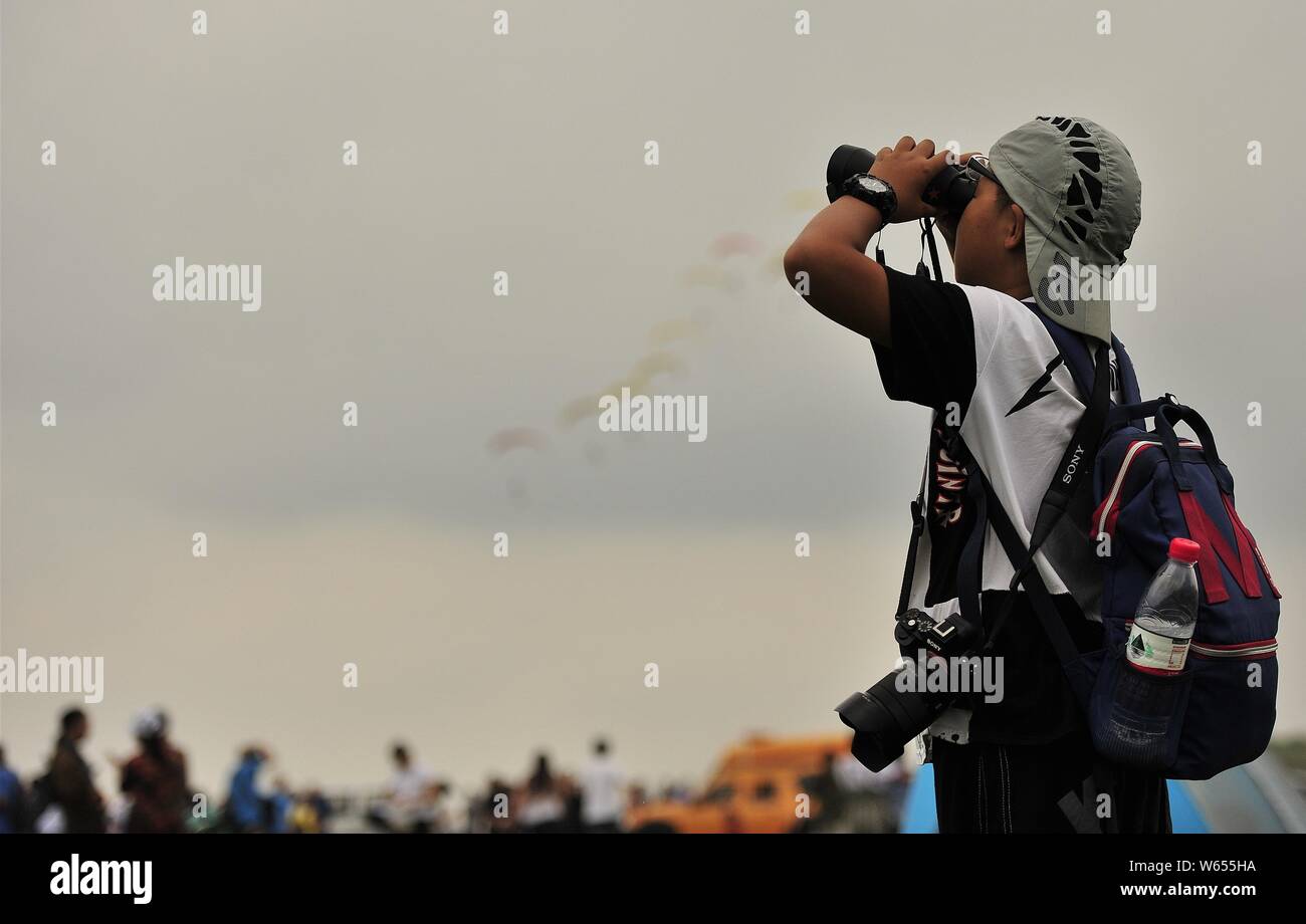 Spectators watch a skydiving performance during the 7th Shenyang Faku ...