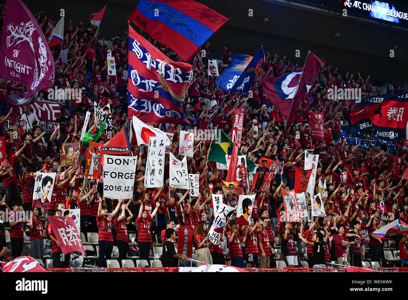 Football fans wave flags and shout slogans to show support for Japan's Kashima Antlers in the ...