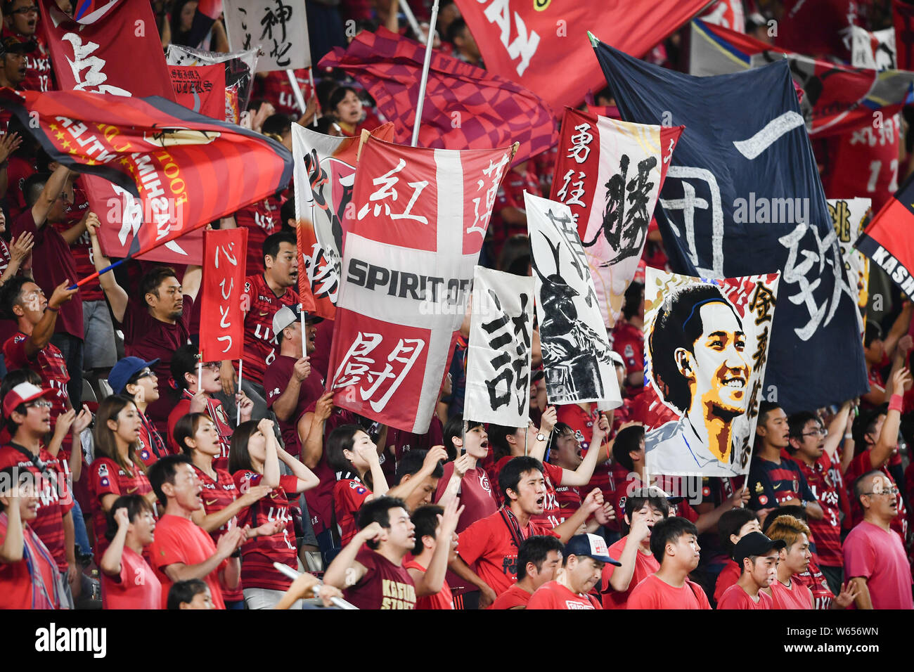 Football fans wave flags and shout slogans to show support for Japan's Kashima Antlers in the ...