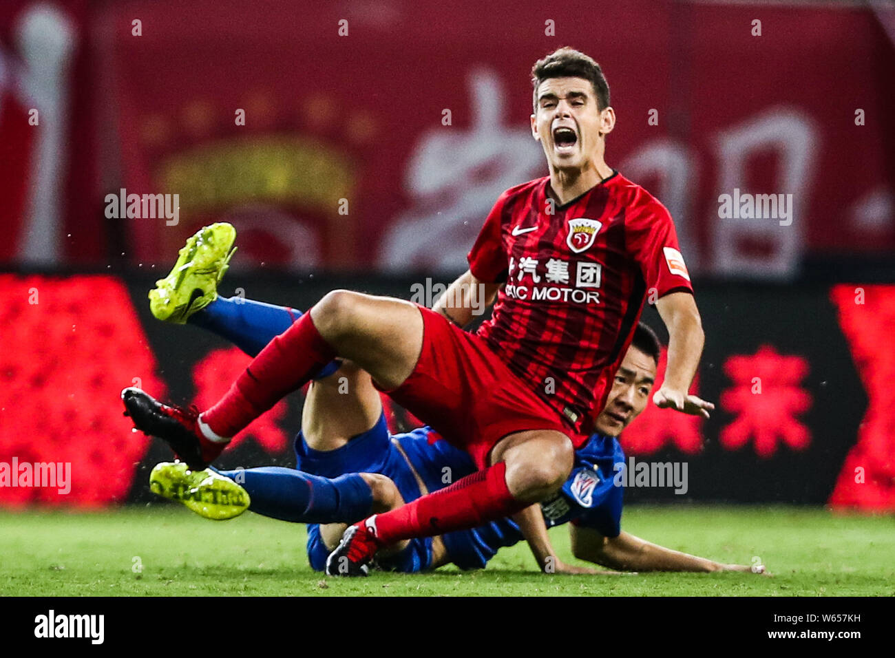 Brazilian football player Oscar of Shanghai SIPG, front, is tumbled ...