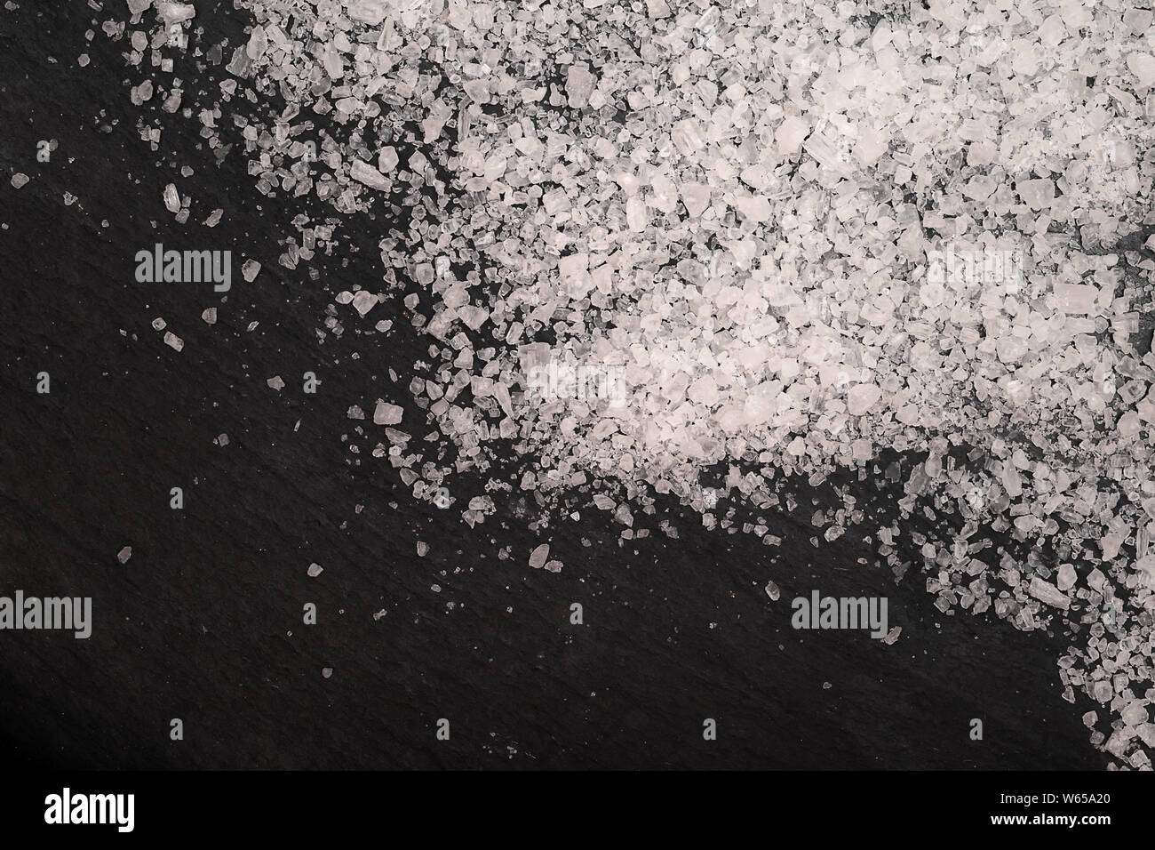 Spilled white sea salt isolated black background Stock Photo - Alamy