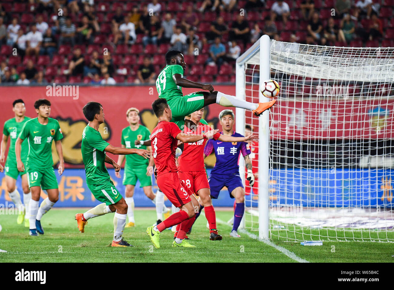 Ivorian football player Kevin Boli of Guizhou Hengfeng, upper, shoots ...