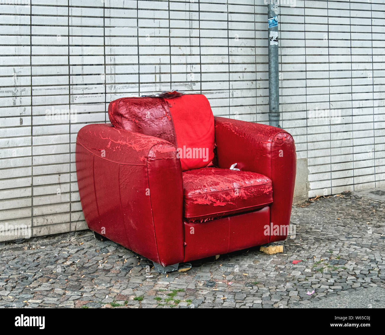 Worn red leather armchair dumped & abandoned on an urban pavement ...