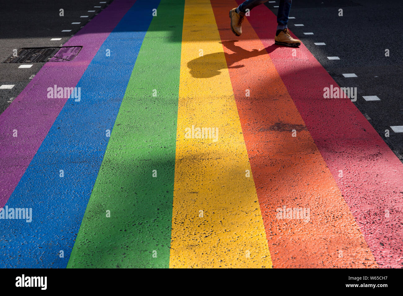 London, UK – July 11, 2019: A man walks on LGBT Pride rainbow painted ...