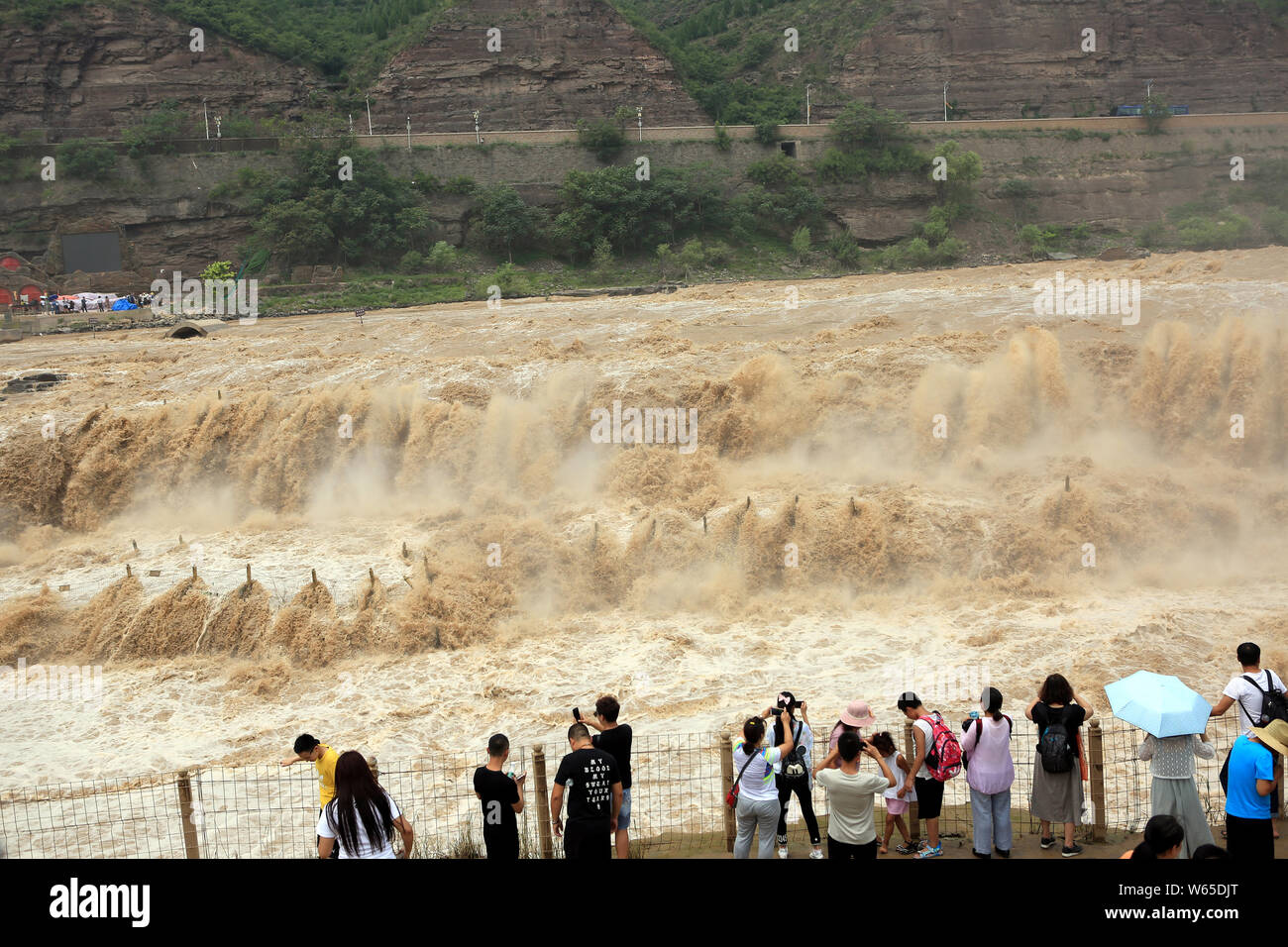 Tourists enjoy the scenes of the roaring waterfall due to torrential ...