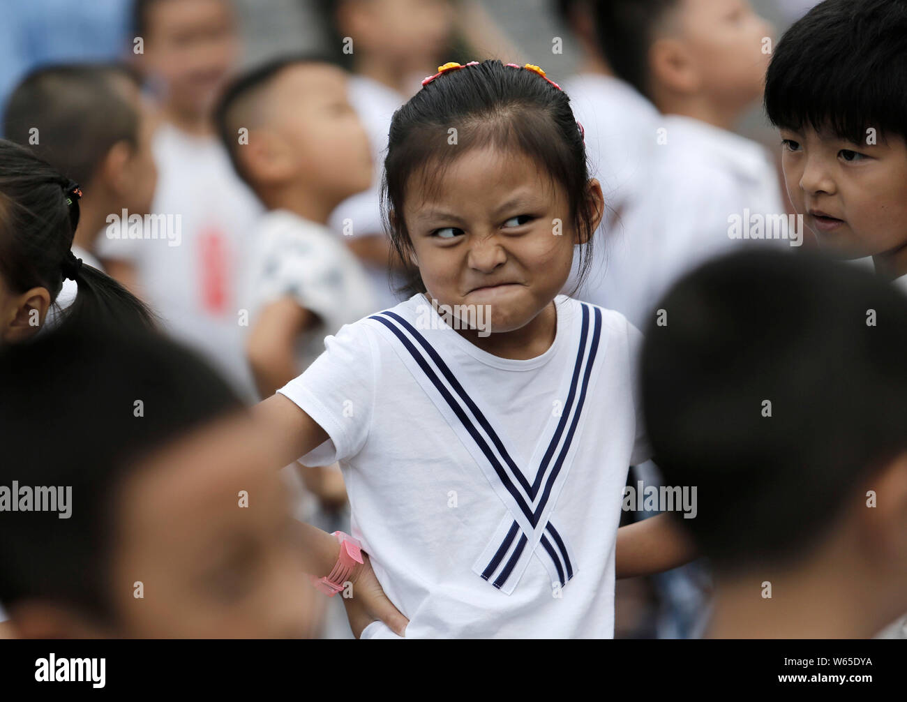 A young student makes faces as she and other students attend a flag ...