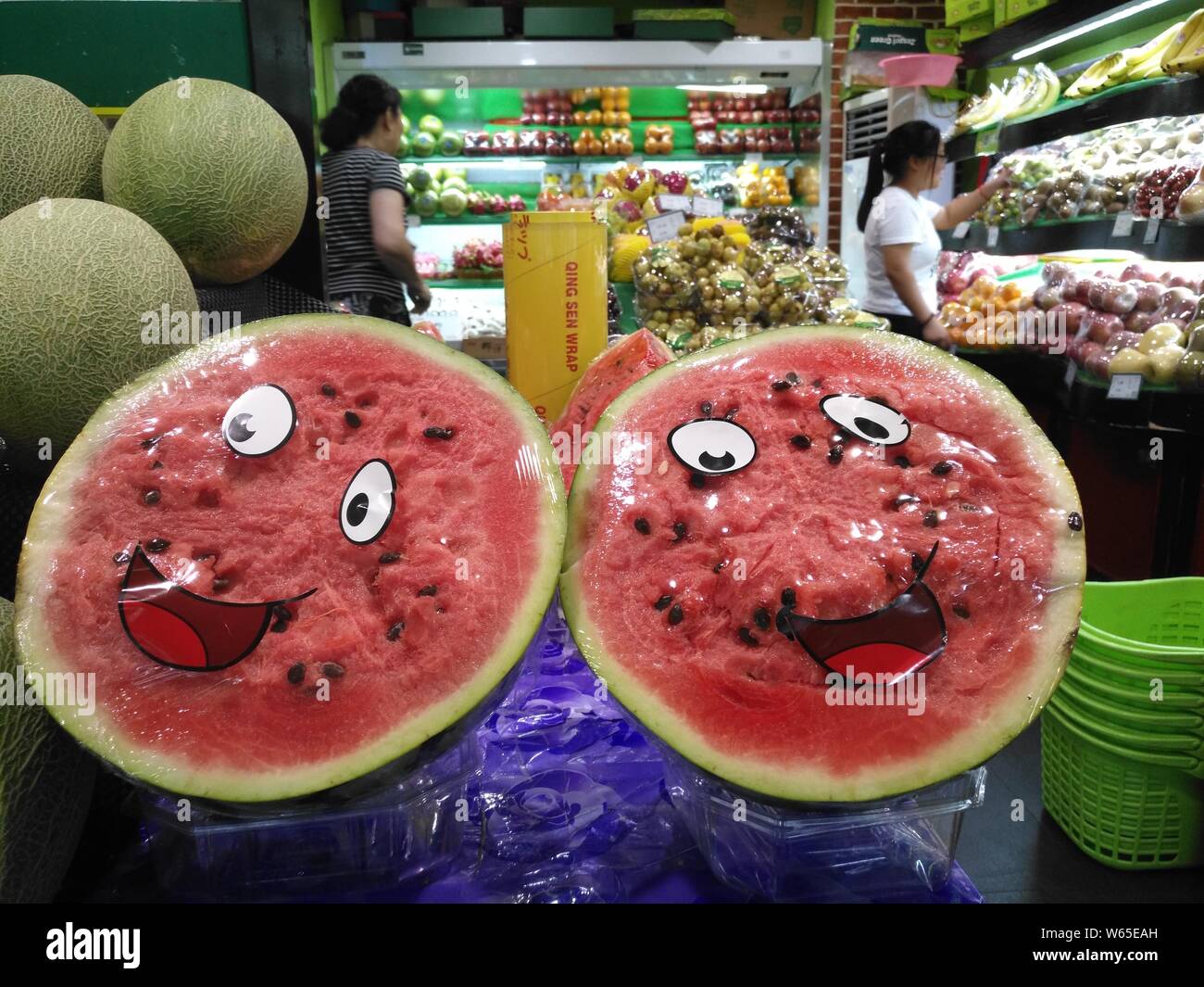 Watermelons covered with smiling cartoon faces on the plastic wrap are ...