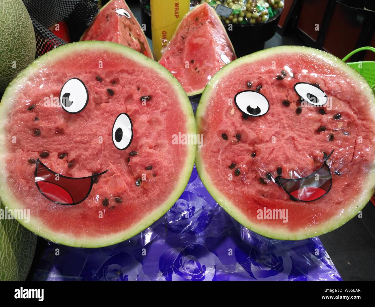 Watermelons covered with smiling cartoon faces on the plastic wrap are ...