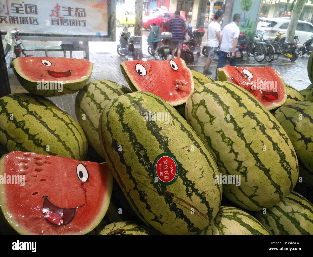 Watermelons covered with smiling cartoon faces on the plastic wrap are ...