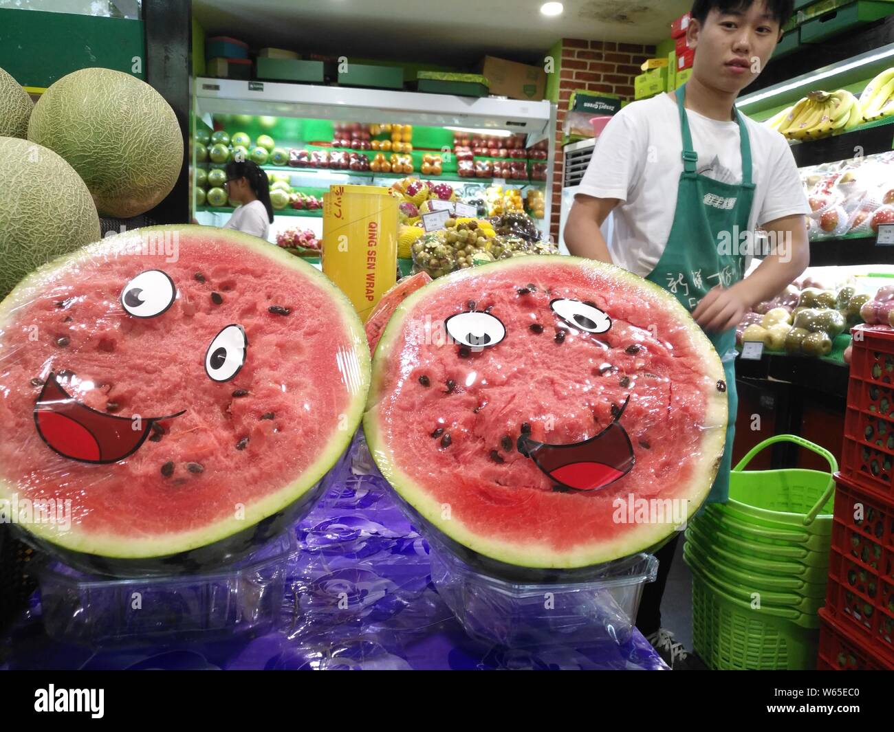 Watermelons covered with smiling cartoon faces on the plastic wrap are ...