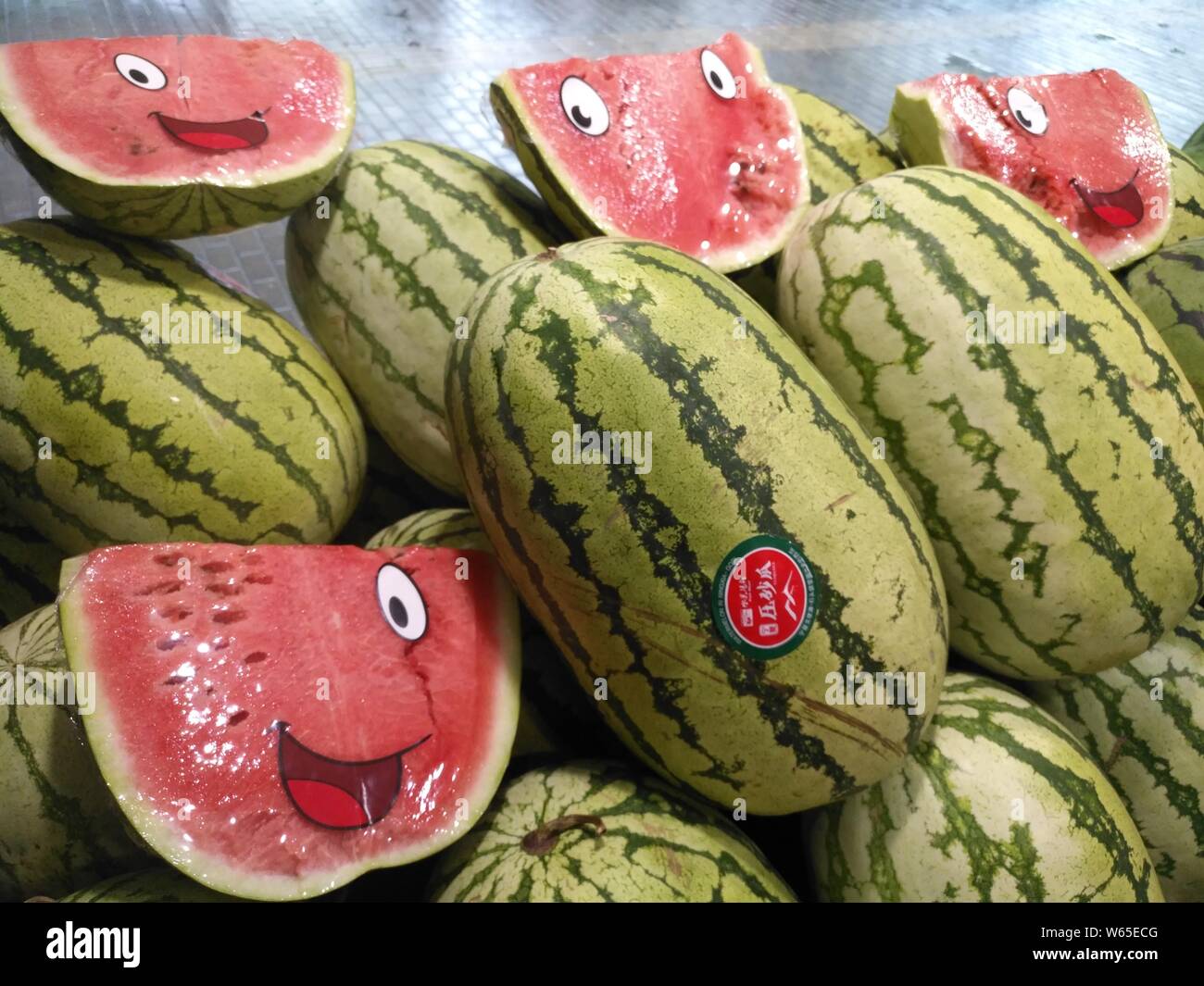 Watermelons covered with smiling cartoon faces on the plastic wrap are ...