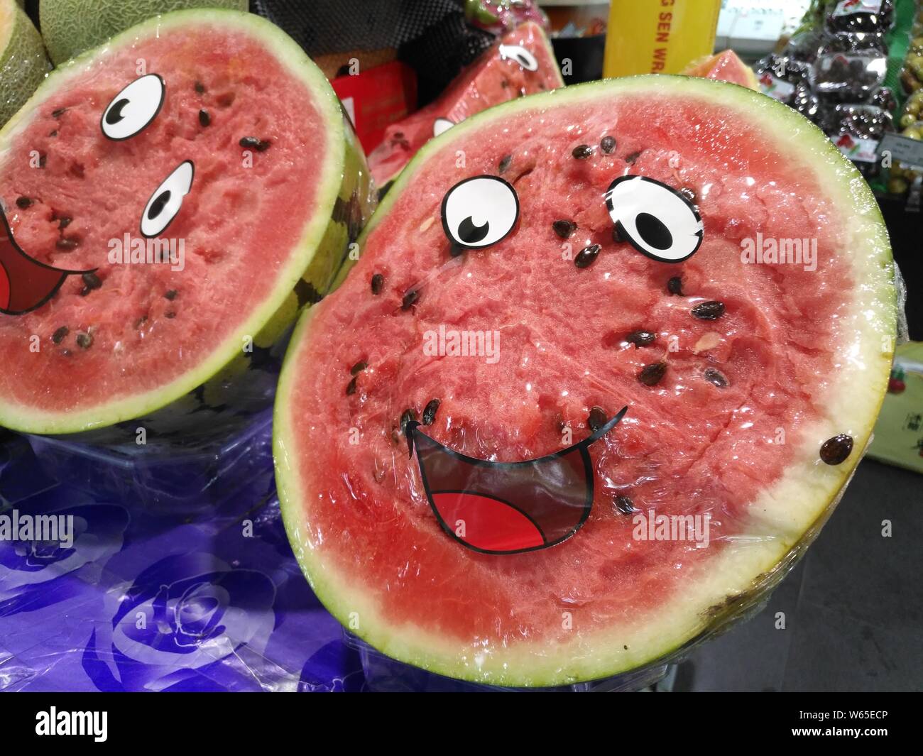 Watermelons covered with smiling cartoon faces on the plastic wrap are ...
