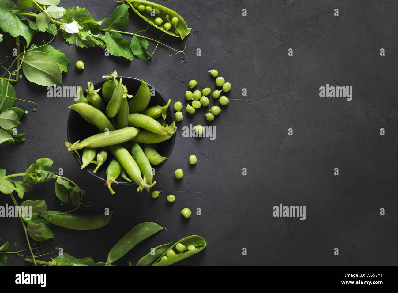Green fresh pea seeds and branches on black concrete background. Space ...