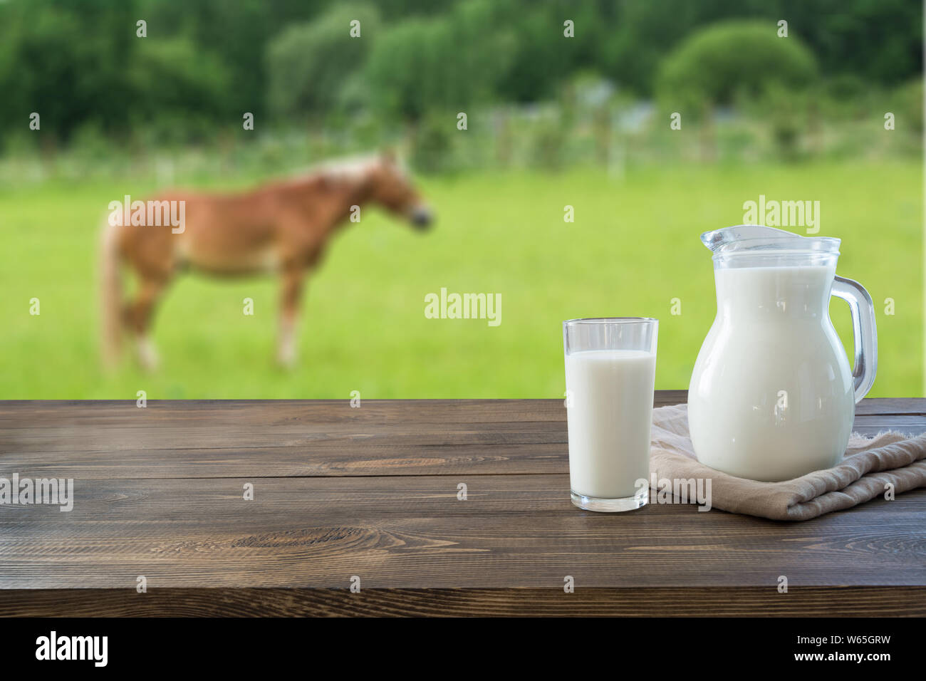 Fresh milk in glass on dark wooden tabletop and blurred landscape with ...