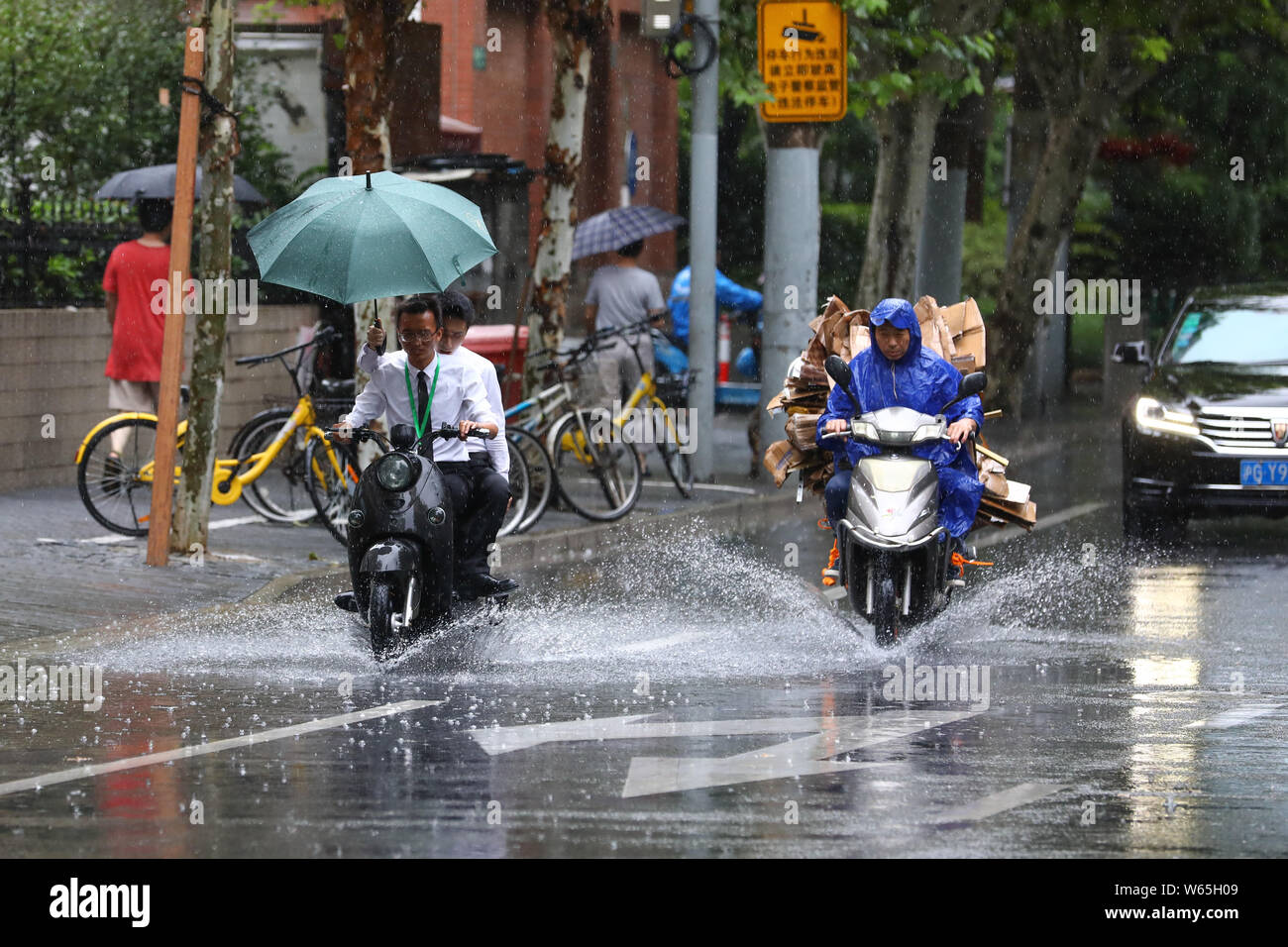 Cyclists shield themselves with umbrellas as they brave strong wind and ...