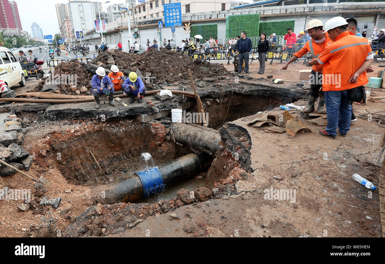 Chinese workers repair a broken water pipeline causing a road collapse ...