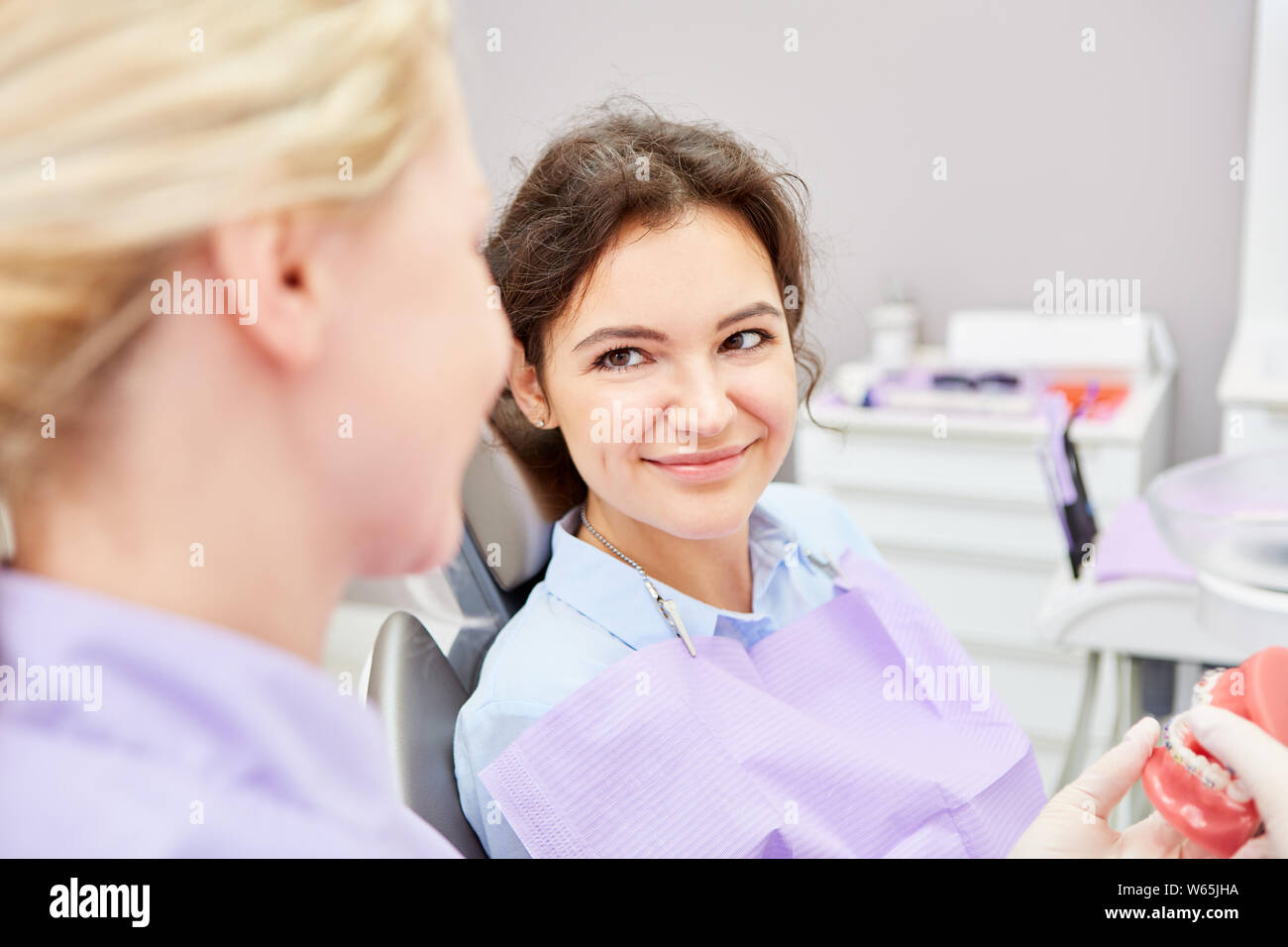 ZFA or dentist explains to a woman as a patient the planned treatment ...