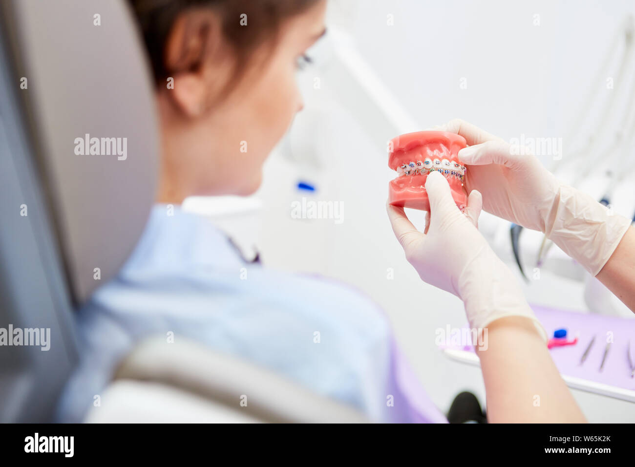 Patient looks attentively at denture model with braces to correct a ...