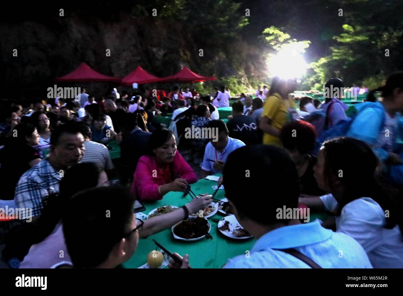 Thousands of tourists eat dinner around tables during a free-flowing ...